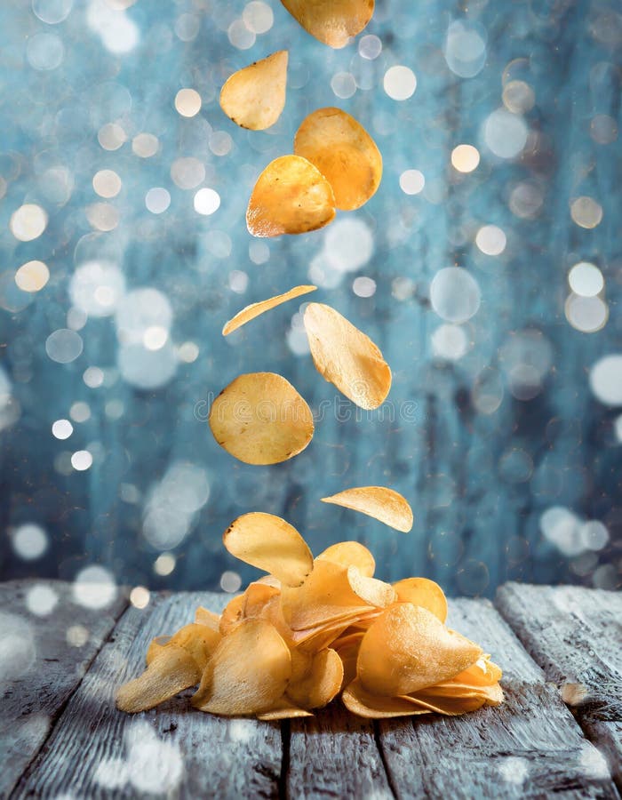 Potato Chips Falling Down on an Old Rustic Wooden Table Stock ...