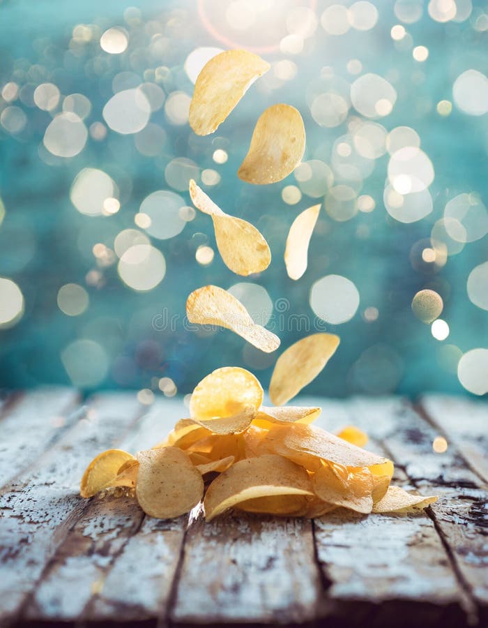 Potato Chips Falling Down on an Old Rustic Wooden Table Stock ...