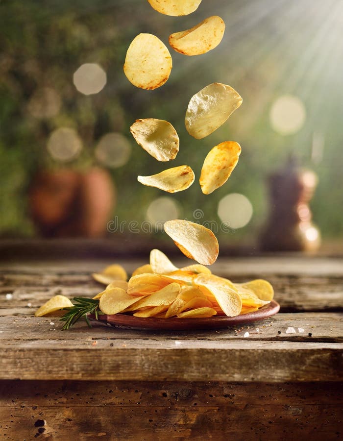 Potato Chips Falling Down on an Old Rustic Wooden Table Stock ...