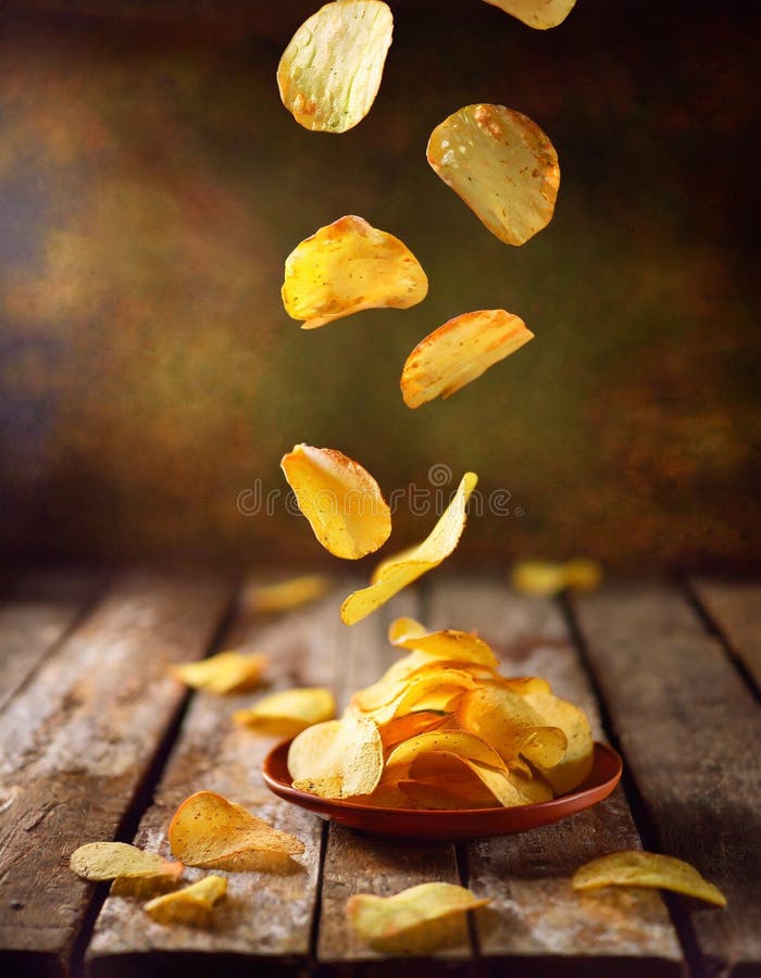Potato Chips Falling Down on an Old Rustic Wooden Table Stock ...