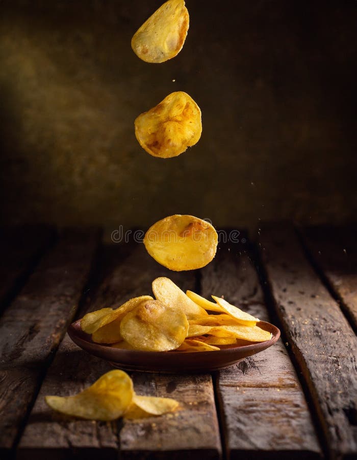 Potato Chips Falling Down on an Old Rustic Wooden Table Stock ...