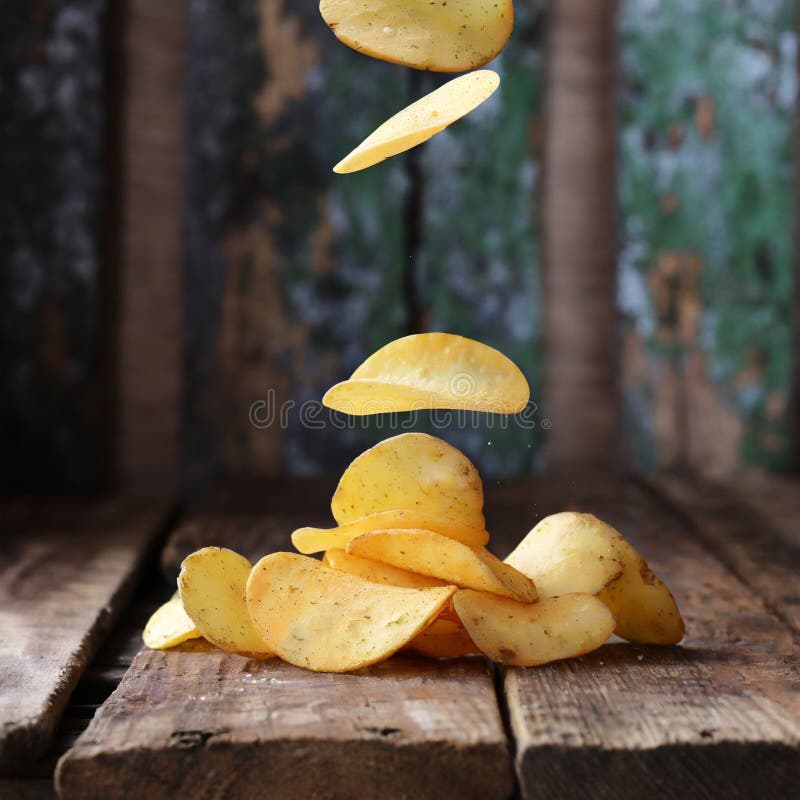 Potato Chips Falling Down on an Old Rustic Wooden Table Stock ...