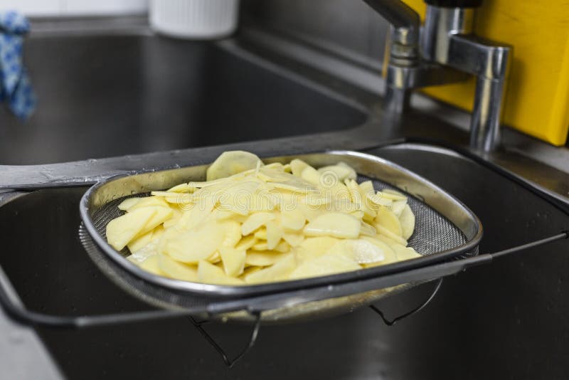 Potato Slices Draining in a Strain on an Industrial Kitchen Sink. Stock ...