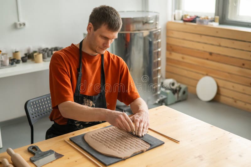 A Potter Cuts a Piece of Rolled Clay with Patterns. Stock Photo - Image ...