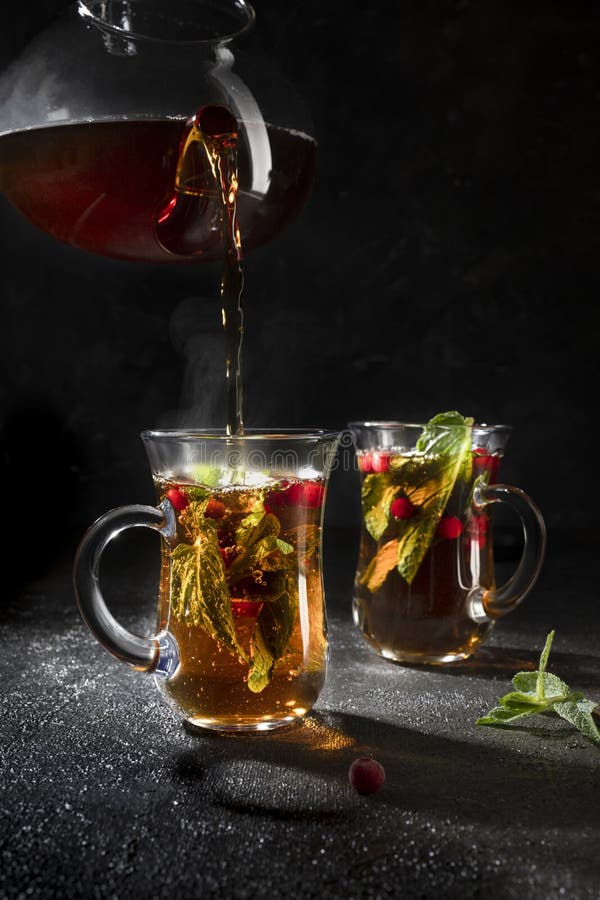 Pour Black Tea from a Transparent Teapot into a Cup on Black Backround ...