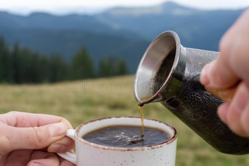 Pouring Coffee from the Pot into the Cup with Mountains on the ...
