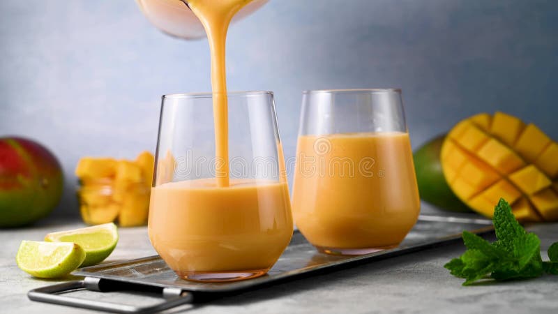 Pouring Mango Smoothie in a Glass with Fresh Mango, Mint and Lime ...