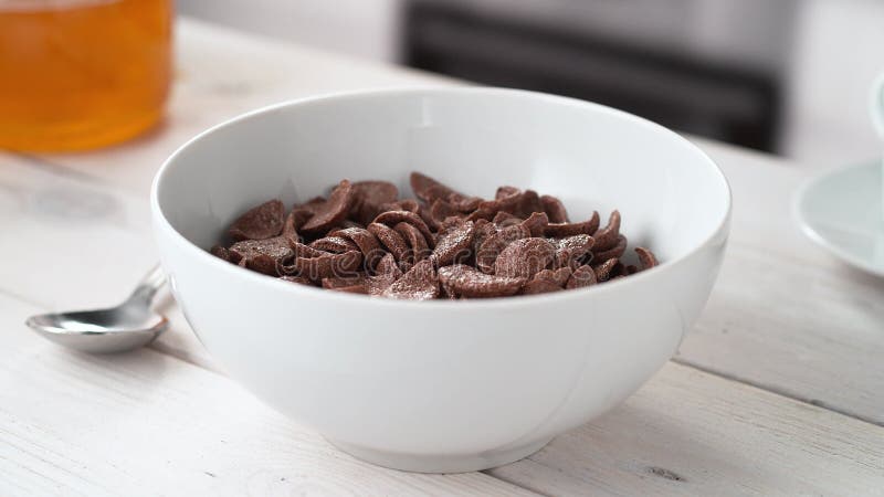 Pouring Milk into the White Bowl Full of Cocoa Shell-Shaped Cereals in ...
