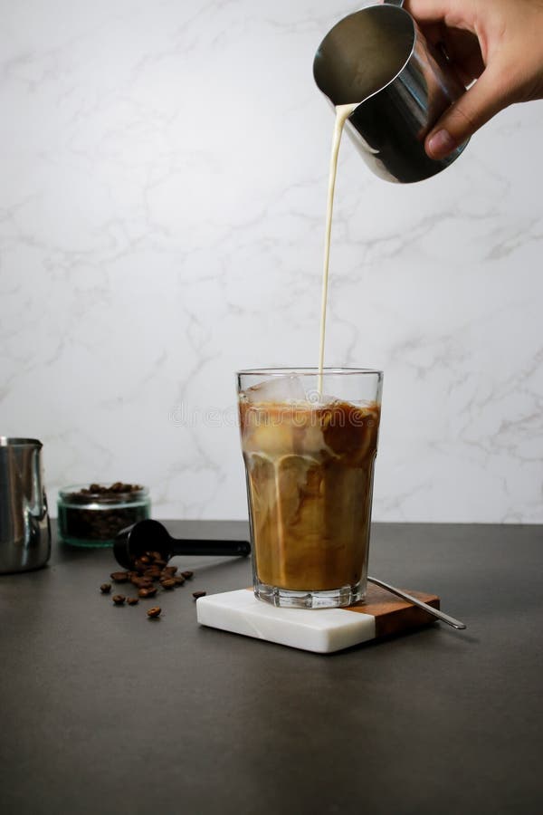 Pouring Oat Milk into Cold Ice Coffee in a Tall Glass, Grey Marble ...