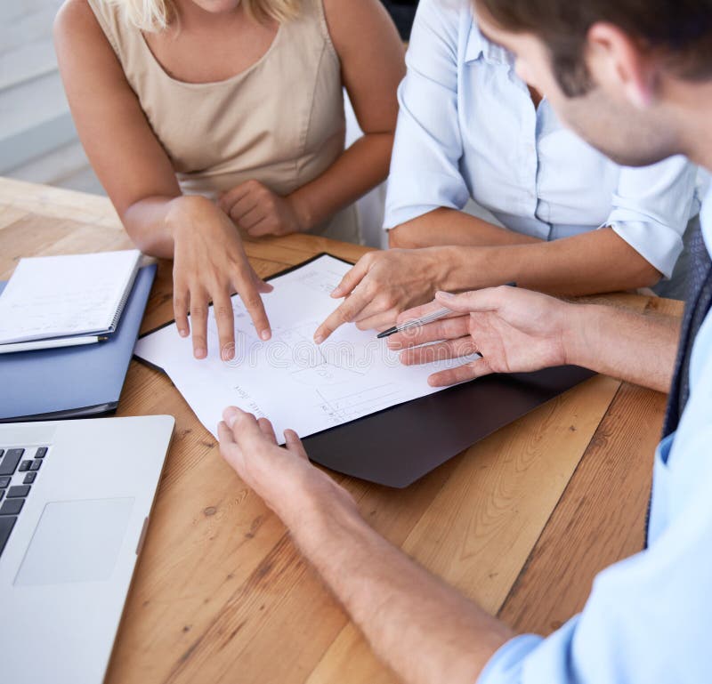 Pouring Over Paperwork. Three Young Executives Sitting Around a Table ...