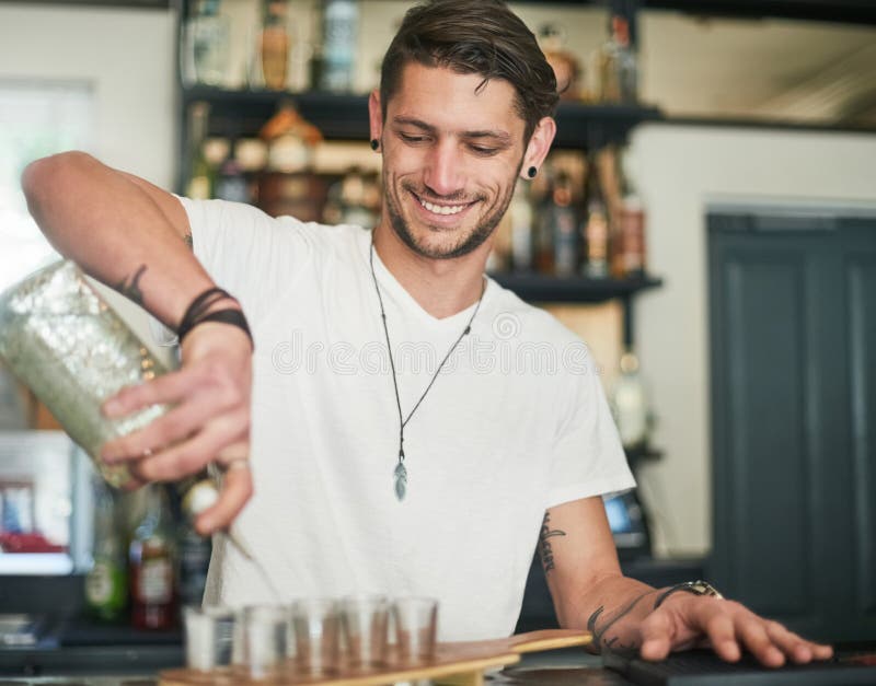 Pouring with Precision. a Happy Young Bartender Pouring Shots Behind ...