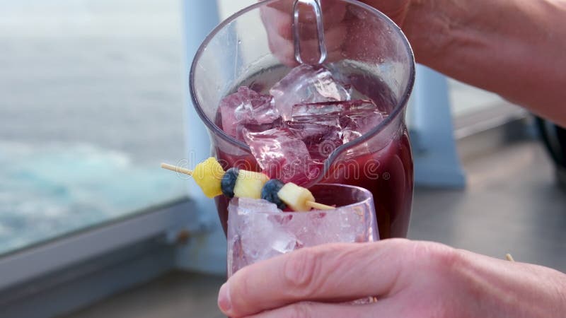 Pouring Raspberry Drink from a Decanter into a Glass with Fruit Against ...