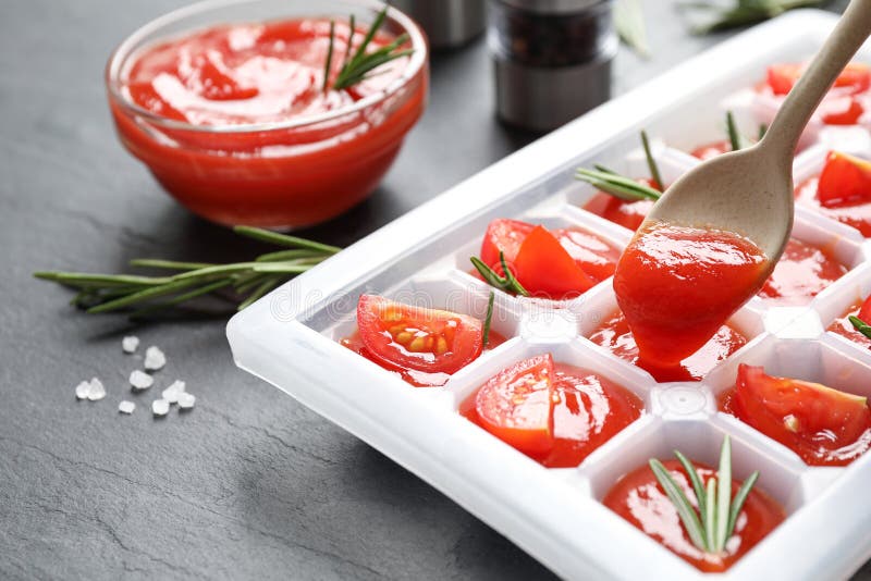 Pouring Sauce into Ice Cube Tray with Tomatoes and Rosemary on Grey ...