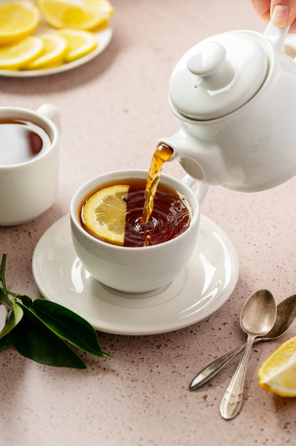 Pouring Tea from Tea Pot, White Ceramic Cup of Black Tea and Lemon ...