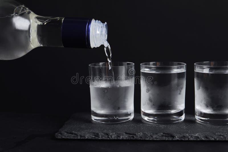 Pouring Vodka from Bottle in Glass on Black Table Stock Photo - Image ...