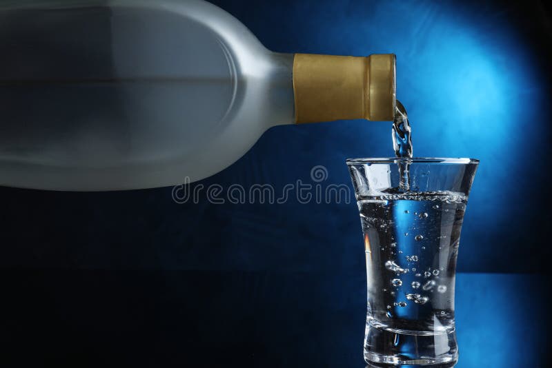Pouring Vodka from Bottle into Shot Glass on Counter Stock Image ...