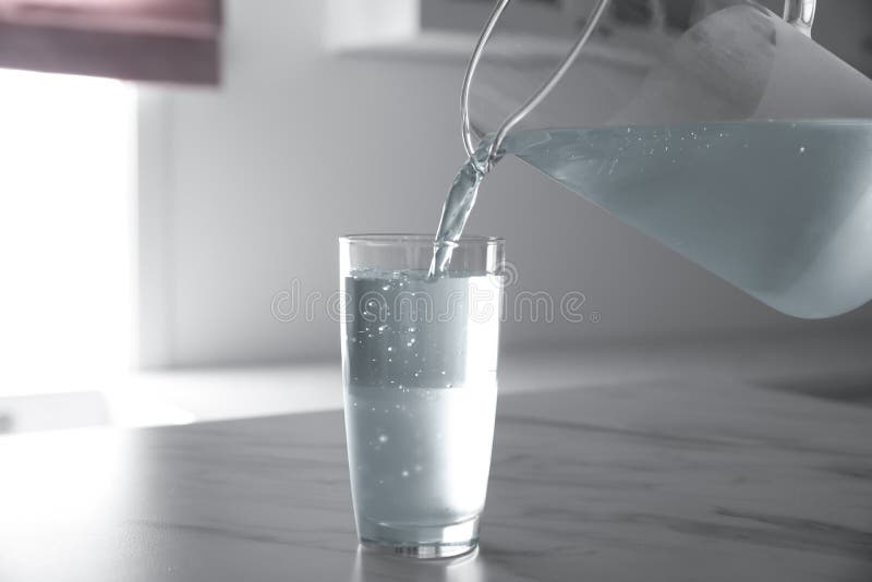Pouring Water from Jug into Glass on Marble Table in Kitchen Stock ...