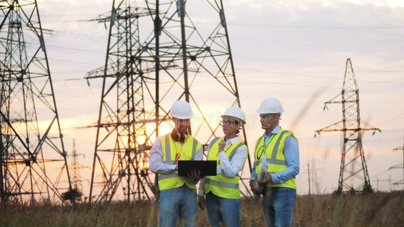 Power Engineers are Talking Near Electrical Transmission Towers Stock ...