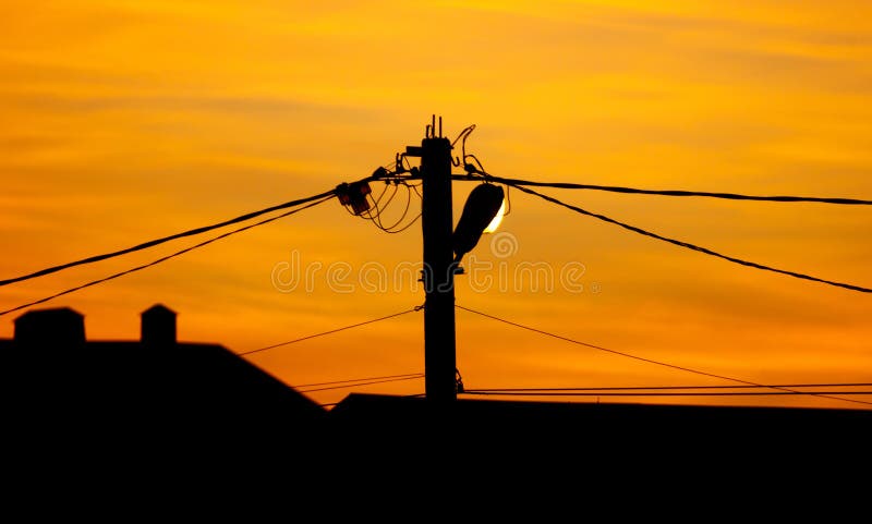 A Power Line Pole is Silhouetted Against a Sunset Stock Image - Image ...