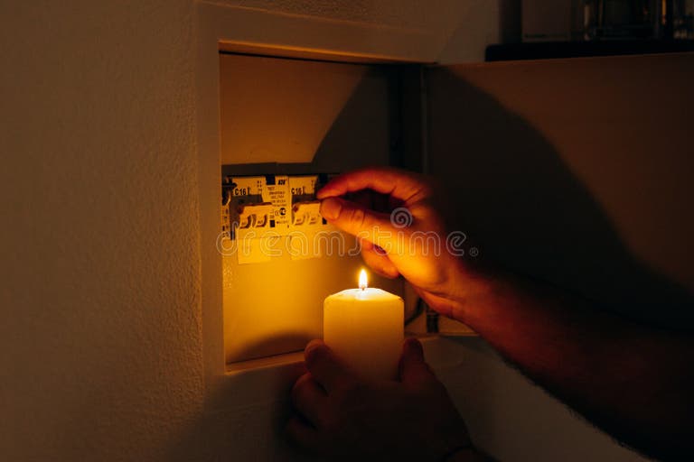 Power Outage. a Man Holds a Candle in Front of an Electrical Panel ...