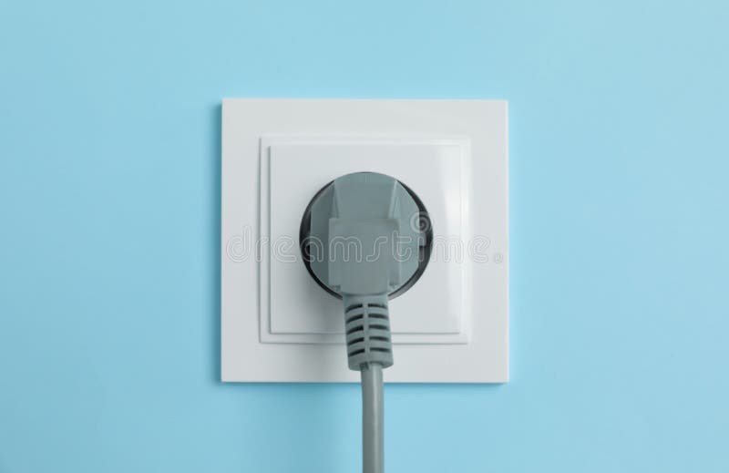 Power Socket with Inserted Plug on Light Blue Wall, Closeup. Electrical ...