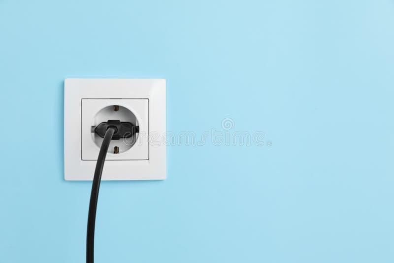 Power Socket with Inserted Plug on Light Blue Wall, Space for Text ...