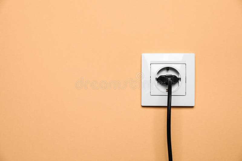 Power Socket with Inserted Plug on Pale Orange Wall, Space for Text ...
