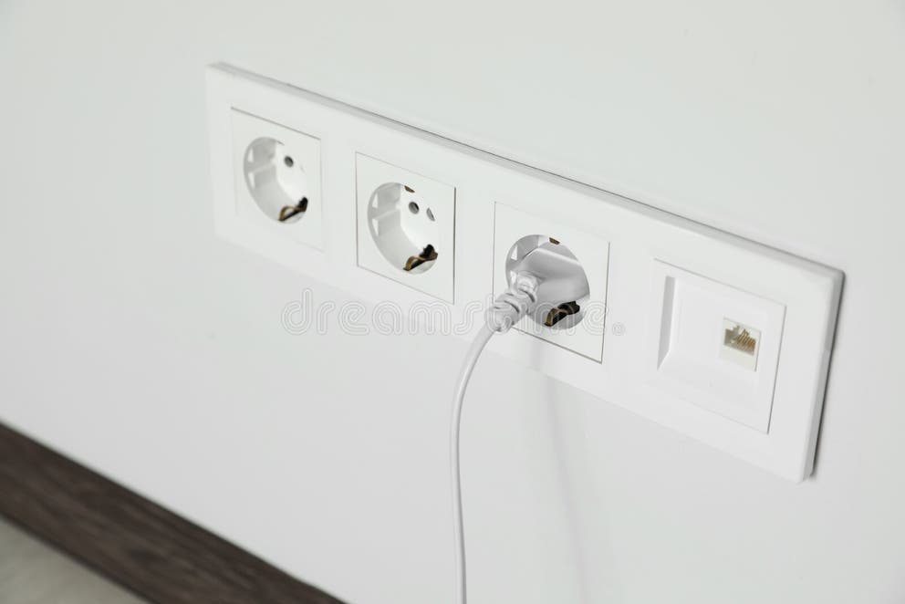 Power Sockets with Inserted Plug on White Wall Indoors, Closeup ...