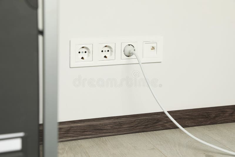 Power Sockets with Inserted Plug on White Wall Indoors. Electrical ...