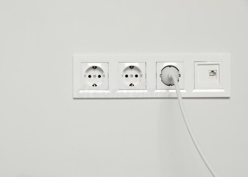 Power Sockets with Inserted Plug on White Wall Indoors. Electrical ...