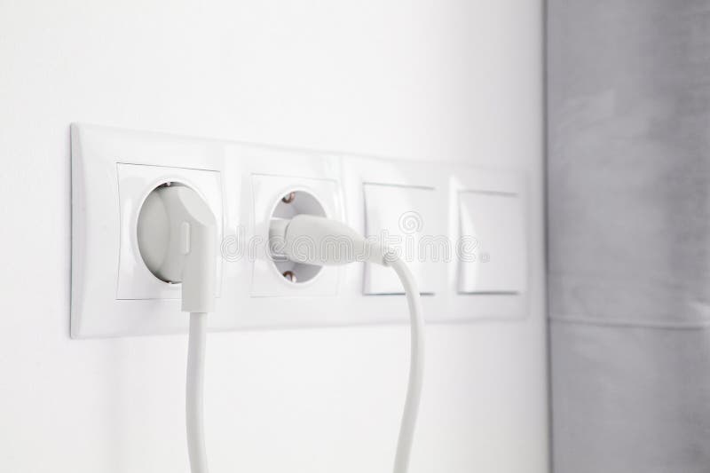Power Sockets with Inserted Plugs and Light Switches on White Wall ...