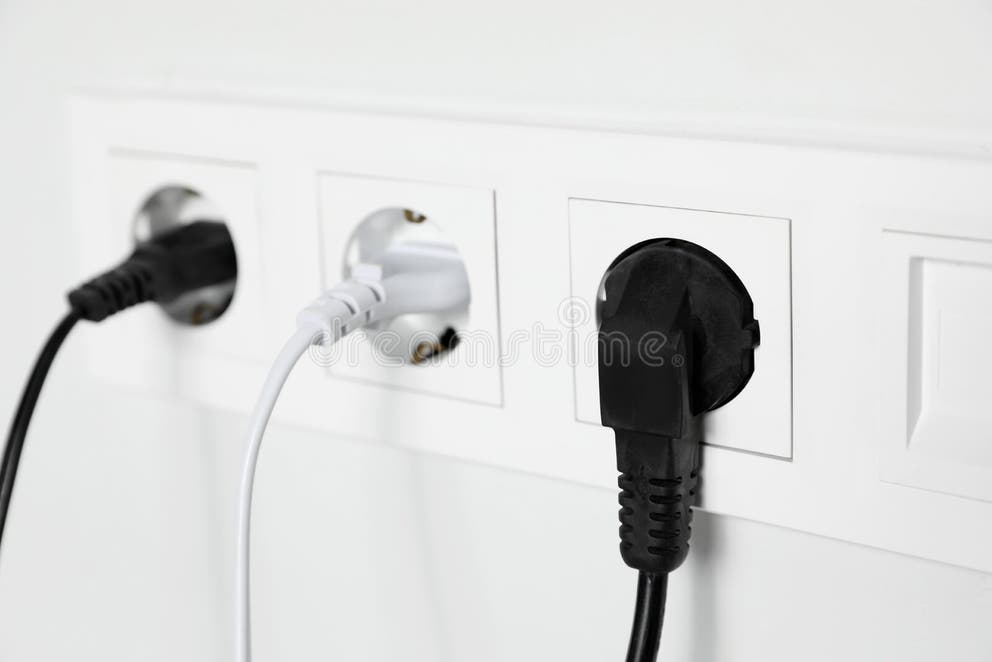 Power Sockets with Inserted Plugs on White Wall, Closeup. Electrical ...