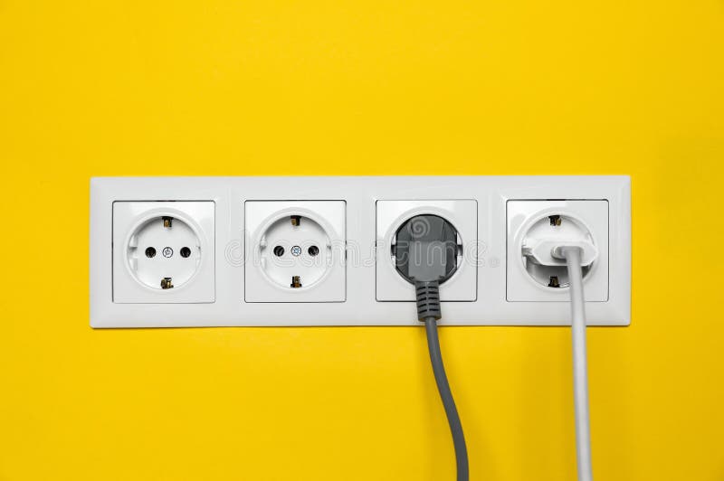 Power Sockets with Inserted Plugs on Yellow Wall. Electrical Supply ...