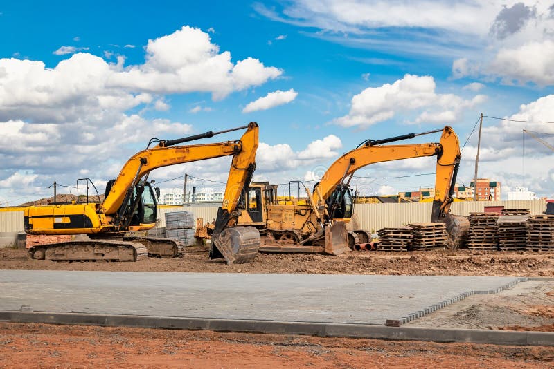 Powerful Excavators at a Construction Site Against a Blue Cloudy Sky ...