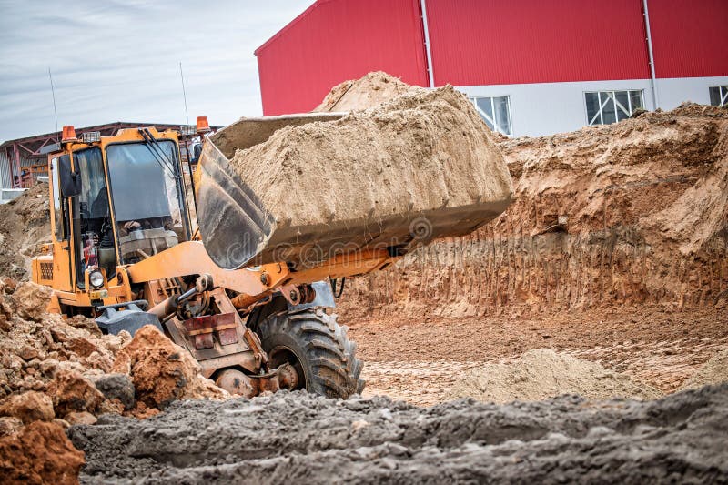 Heavy Machinery at Work Moving Sand on a Construction Site Near a Red ...