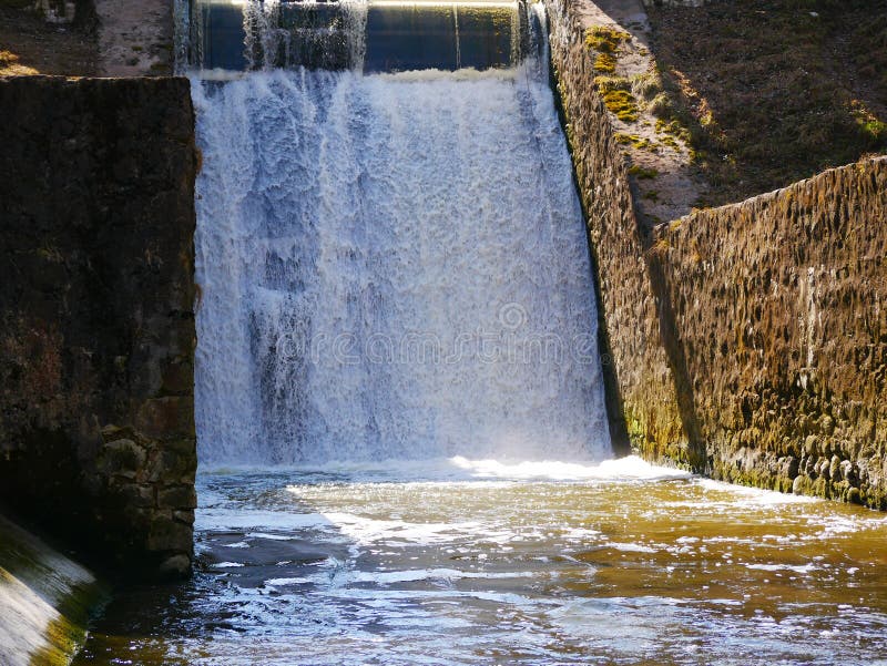 A Powerful Stream of Water Flows through the Stone Dam. Sunny Day ...