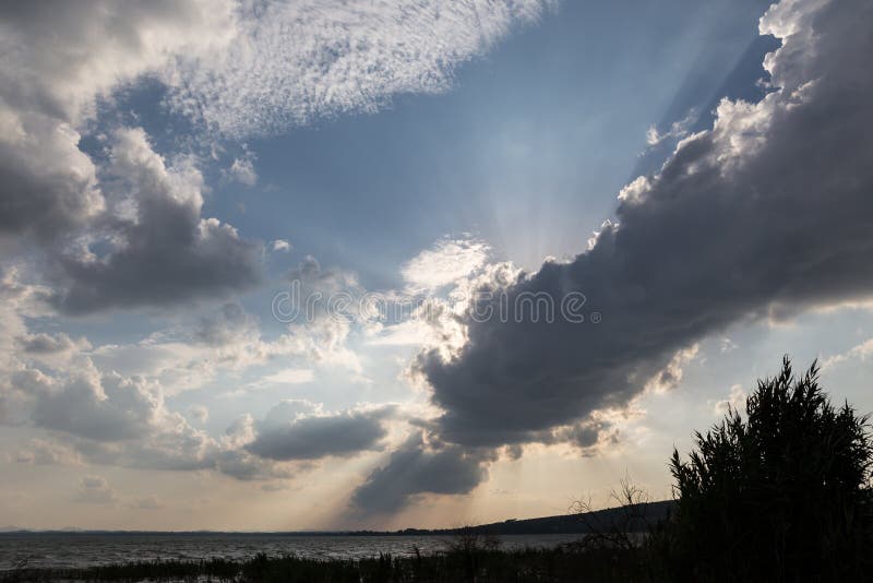 Powerful Sun Rays Coming Out through Some Clouds Above a Lake Sh Stock ...