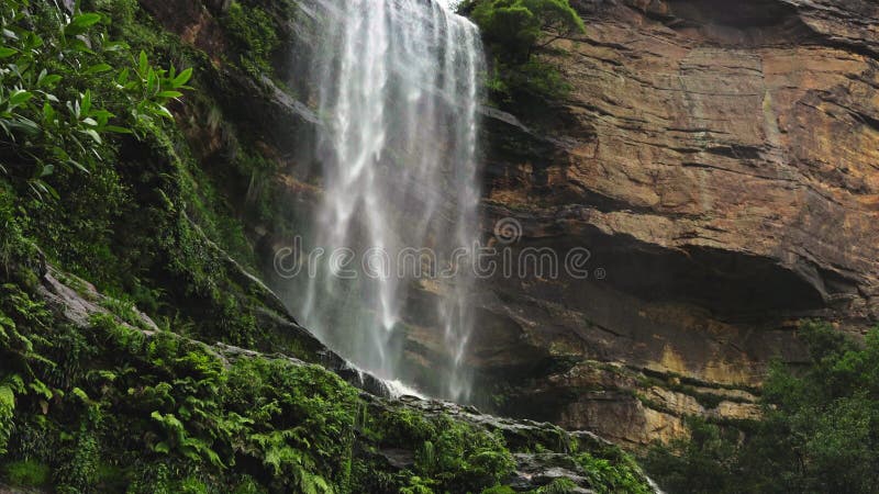 A Powerful Waterfall Cascades Over Rugged Cliffs, Surrounded by Vibrant ...