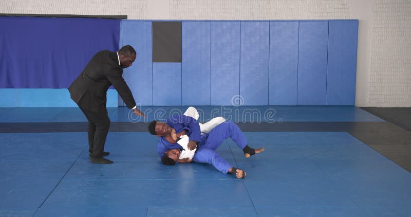 Practicing Judo, Athletes Grappling on Mat while Coach Instructing in ...