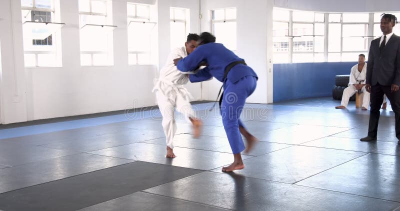 Practicing Judo, Athletes Sparring on Mat while Instructor Observes in ...