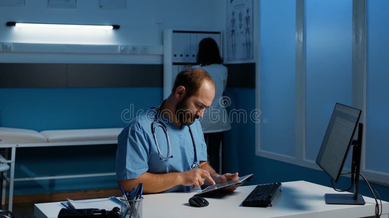 Practitioner Assistant Sitting at Desk Holding Tablet Computer ...