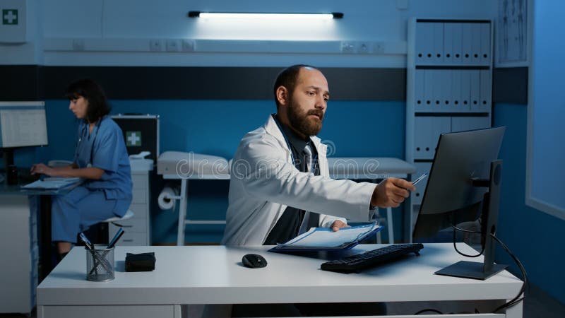 Practitioner Doctor Standing at Desk Looking at Data Expertise on ...