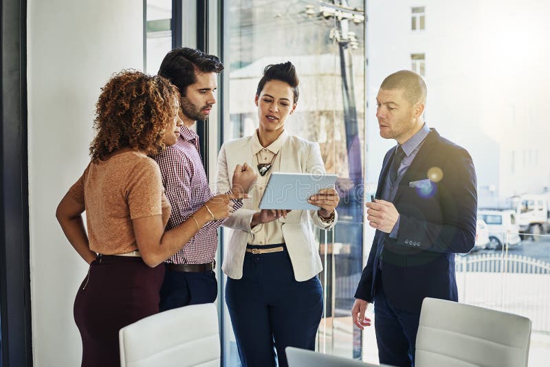 Pre-meeting Prep. Shot of a Group of Colleagues Using a Tablet while ...