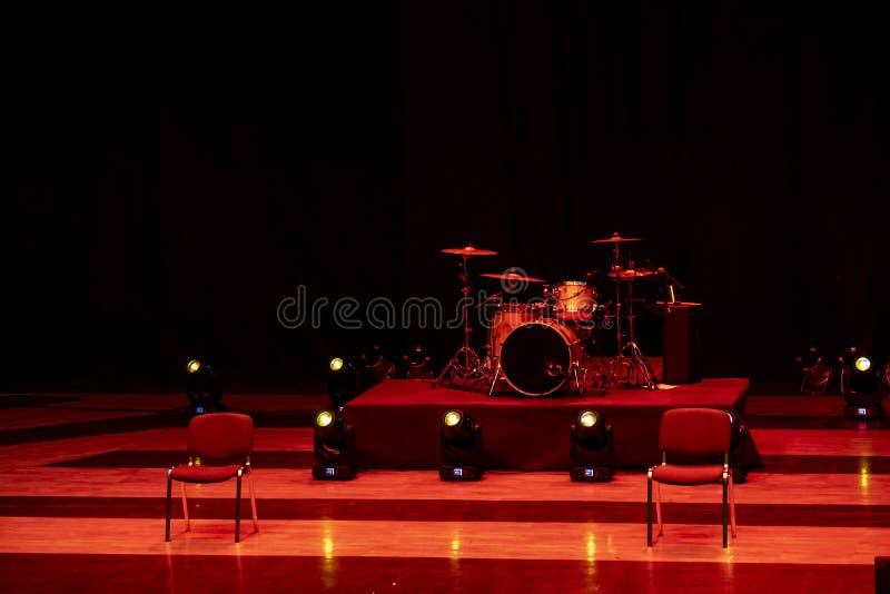 A Pre-performance Scene in Red Light with a Drum Set in the Middle ...
