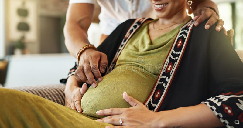 Pregnant Couple And Hands On Tummy On Sofa With Bonding Stomach Touch
