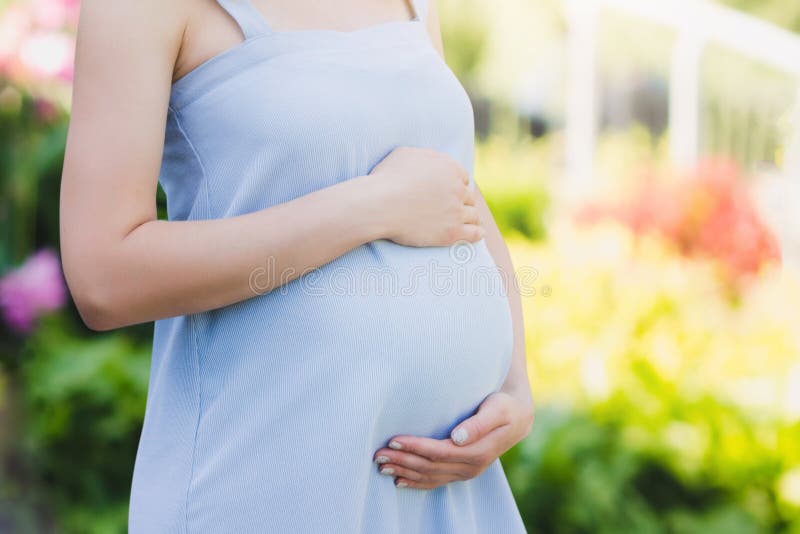 A Pregnant Woman In A Blue Dress On A Nature Background Close Up