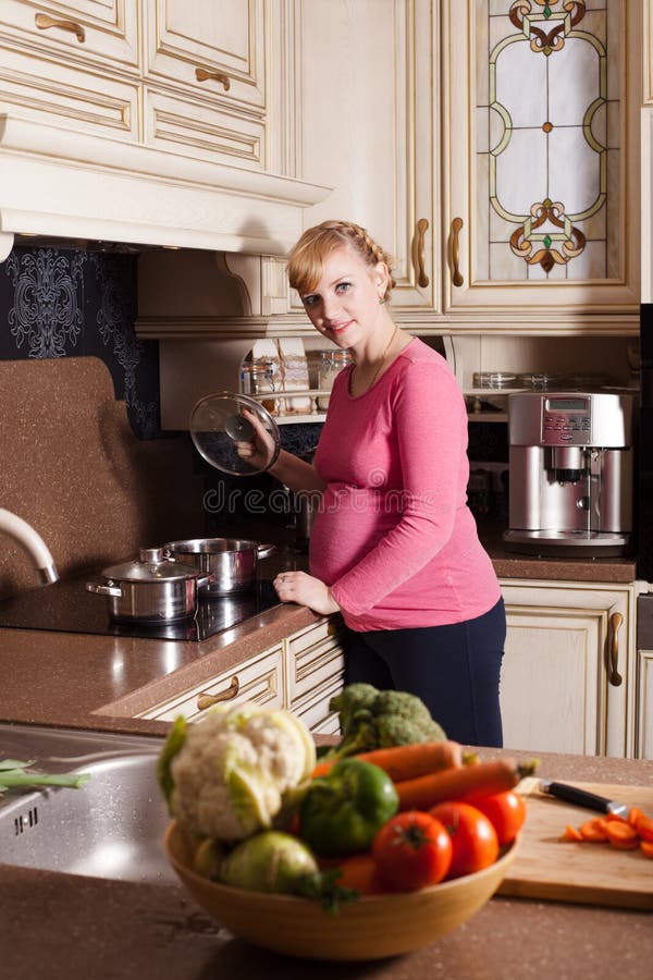 Pregnant woman is cooking stock image. Image of people - 64110497