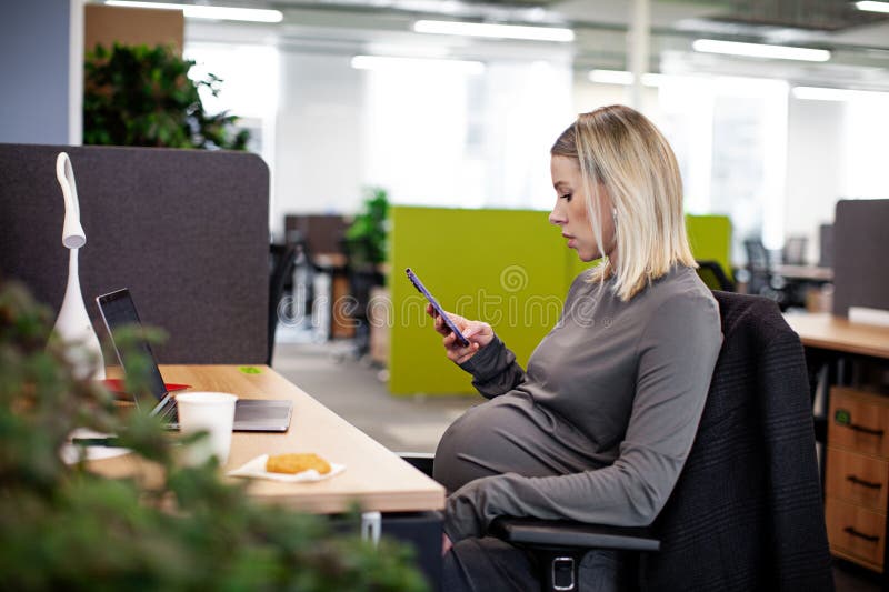 Pregnant Woman Standing in Office Cubicle, Surrounded by a Desk ...