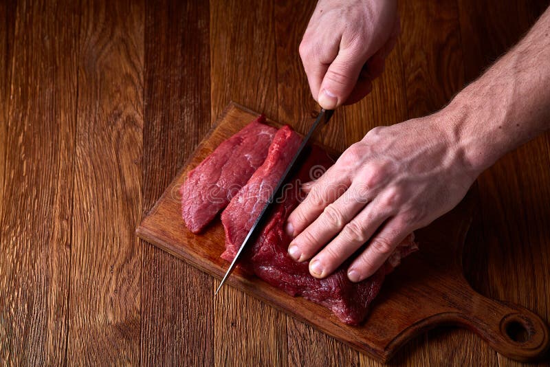 Strong Professional Man`s Hands Cutting Raw Beefsteak, Selective Focus ...