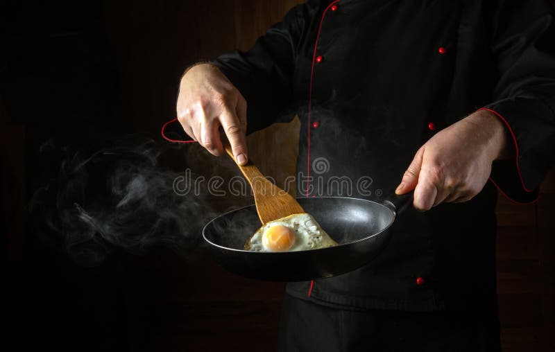 Preparing Fried Eggs in the Tavern Kitchen. a Chef Flips an Egg in a ...